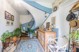 Um interior aconchegante com uma escadaria em espiral, móveis de madeira e vários objetos decorativos.