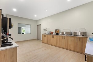 Cozinha moderna com armários de madeira, espaço para café e janela que oferece iluminação natural.
