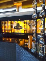 Interior de restaurante com área de bar, um letreiro com a inscrição "Bano Negro Restaurant" e várias taças de vinho expostas em prateleiras.