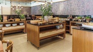 Um café moderno com mobiliário de madeira, um balcão central de atendimento e plantas decorativas.