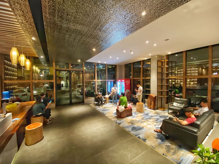 Um lobby moderno com áreas de estar, balcão de recepção e grandes janelas.