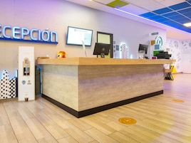 Uma receção com um ecrã digital, um computador e um sinal na parede.