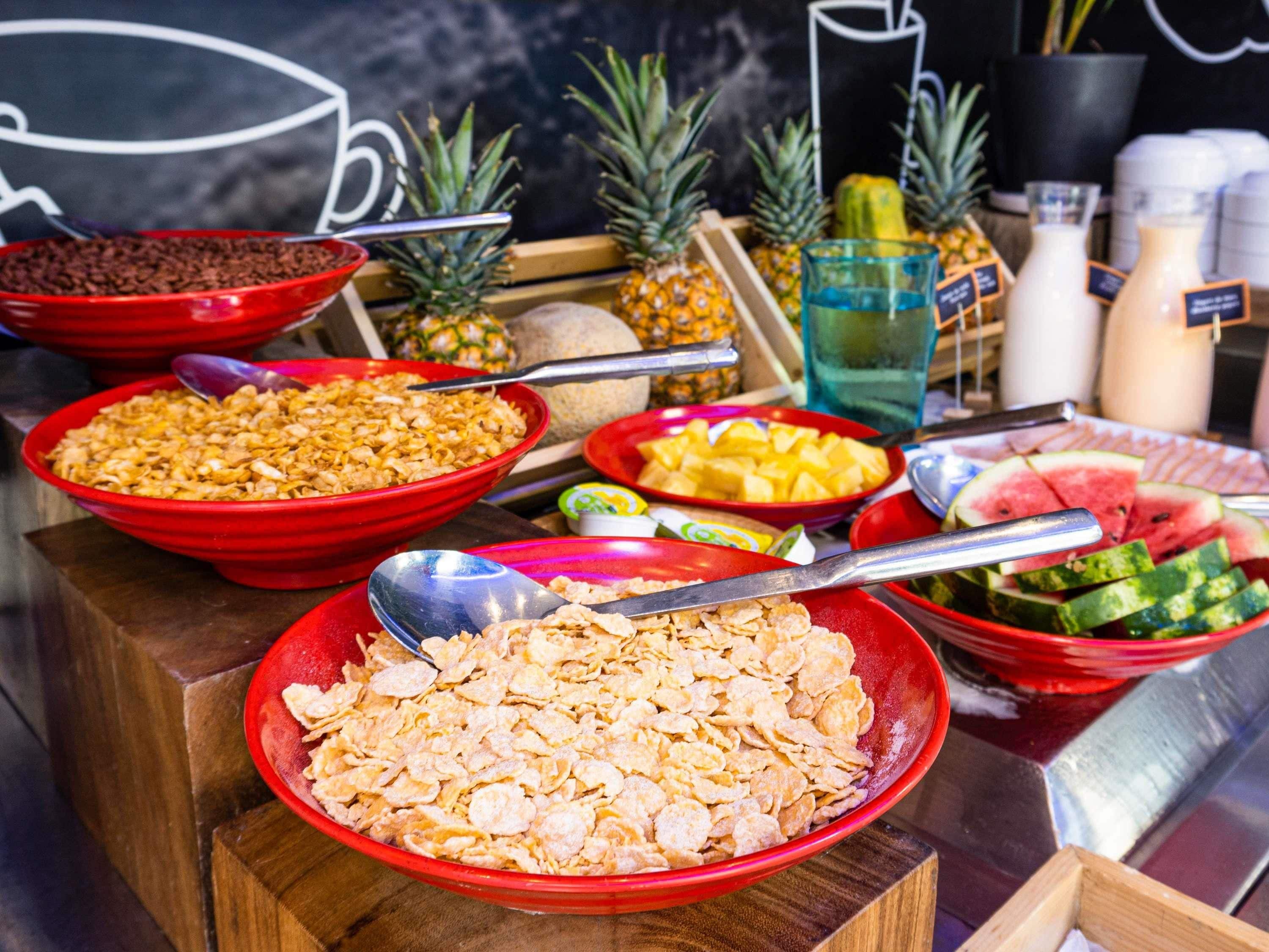 Buffet com diversos alimentos, incluindo cereais, frutas e bebidas.