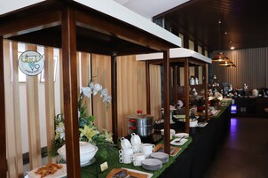 Disposição de buffet com diversos pratos, utensílios, uma placa com a palavra 'Friendship' e um arranjo floral decorativo.