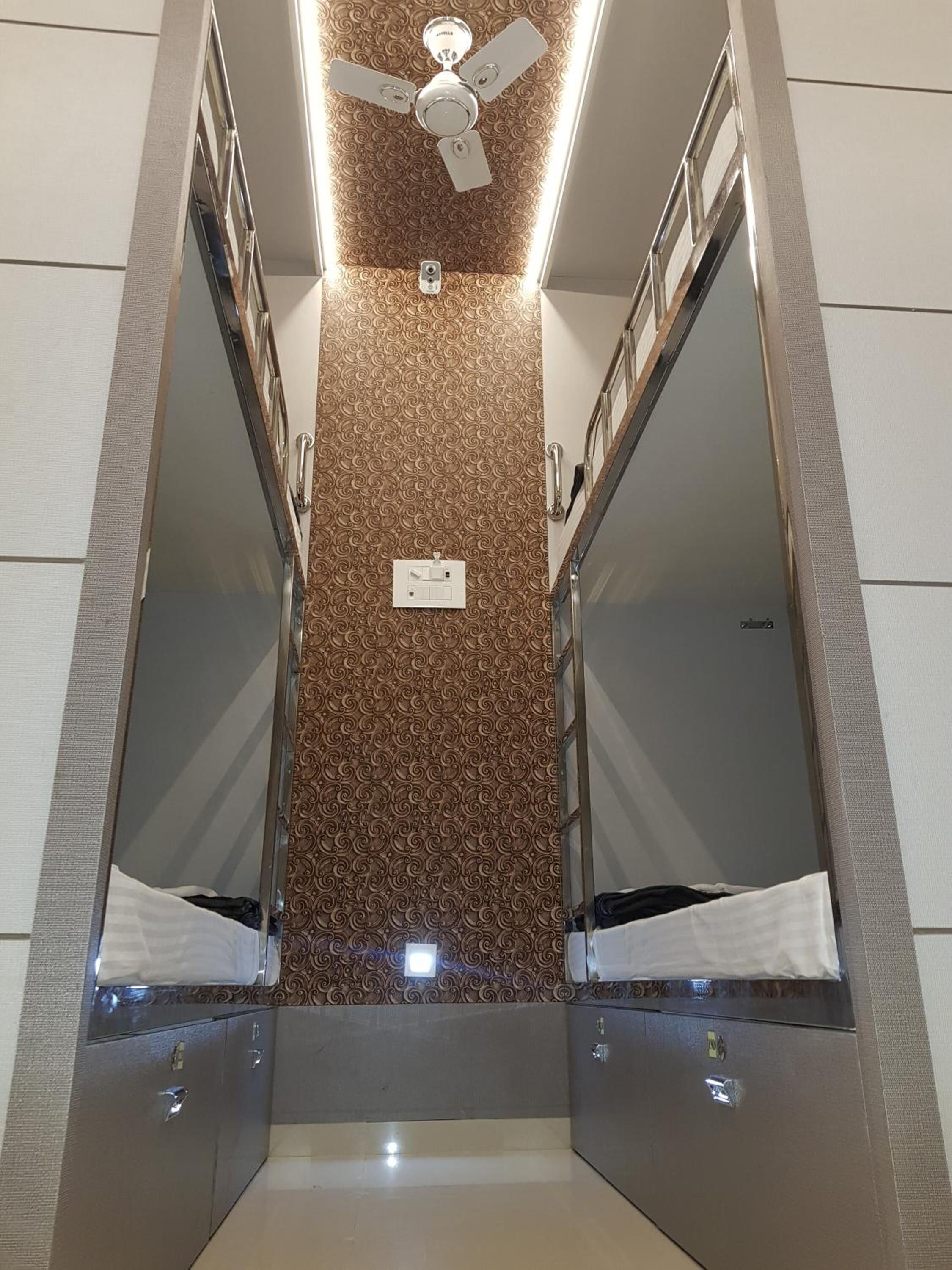Um banheiro com ventilador no teto, duas espelhas e porta-toalhas.