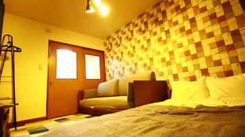 Quarto com cama, sofá, porta de madeira e parede quadriculada.