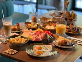 Um buffet de café da manhã com diversos pratos, incluindo ovos, pães de confeito e frutas.