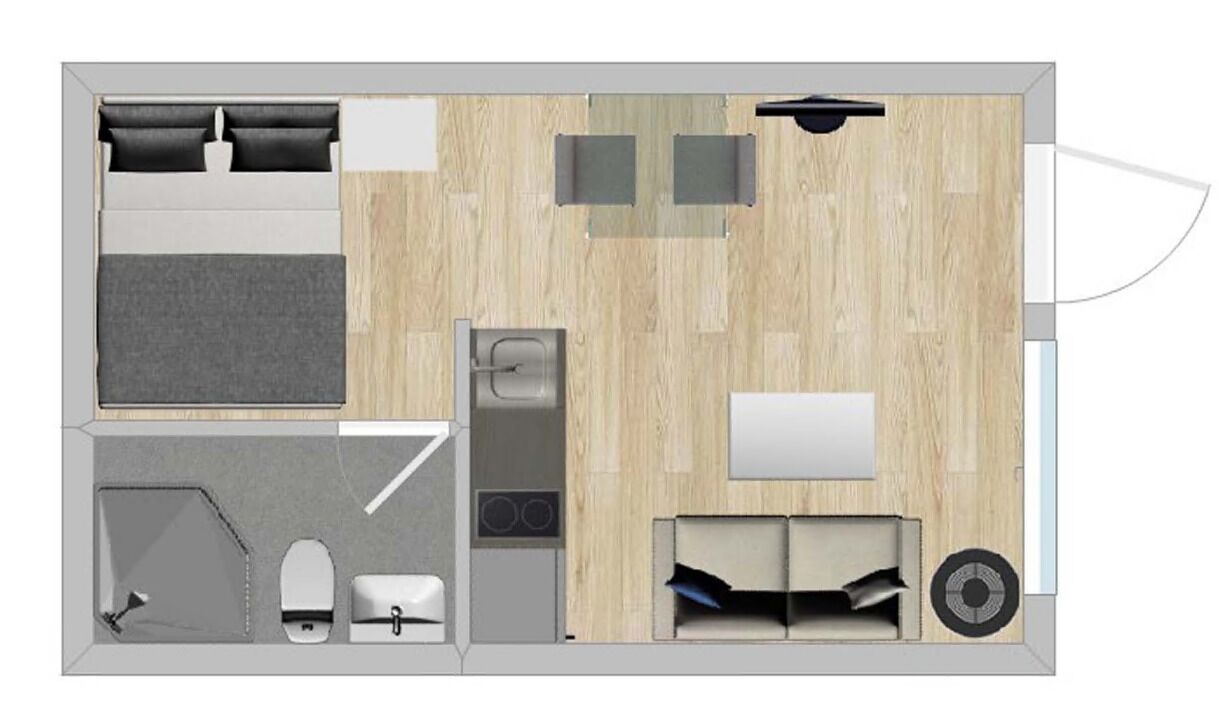 Quarto de hotel compacto com cama, um pequeno espaço de estar, cozinha compacta e banheiro.