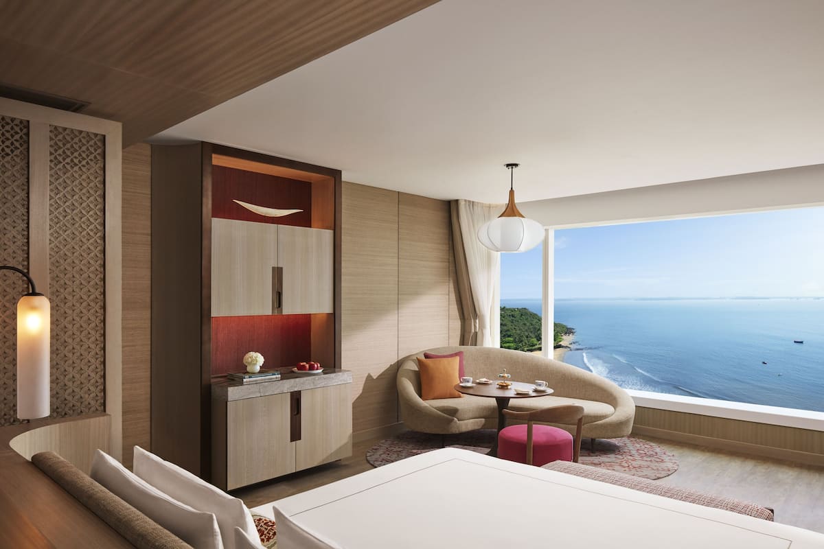 Quarto de hotel moderno com uma grande janela com vista para o mar, um espaço de estar acolhedor e um minibar.