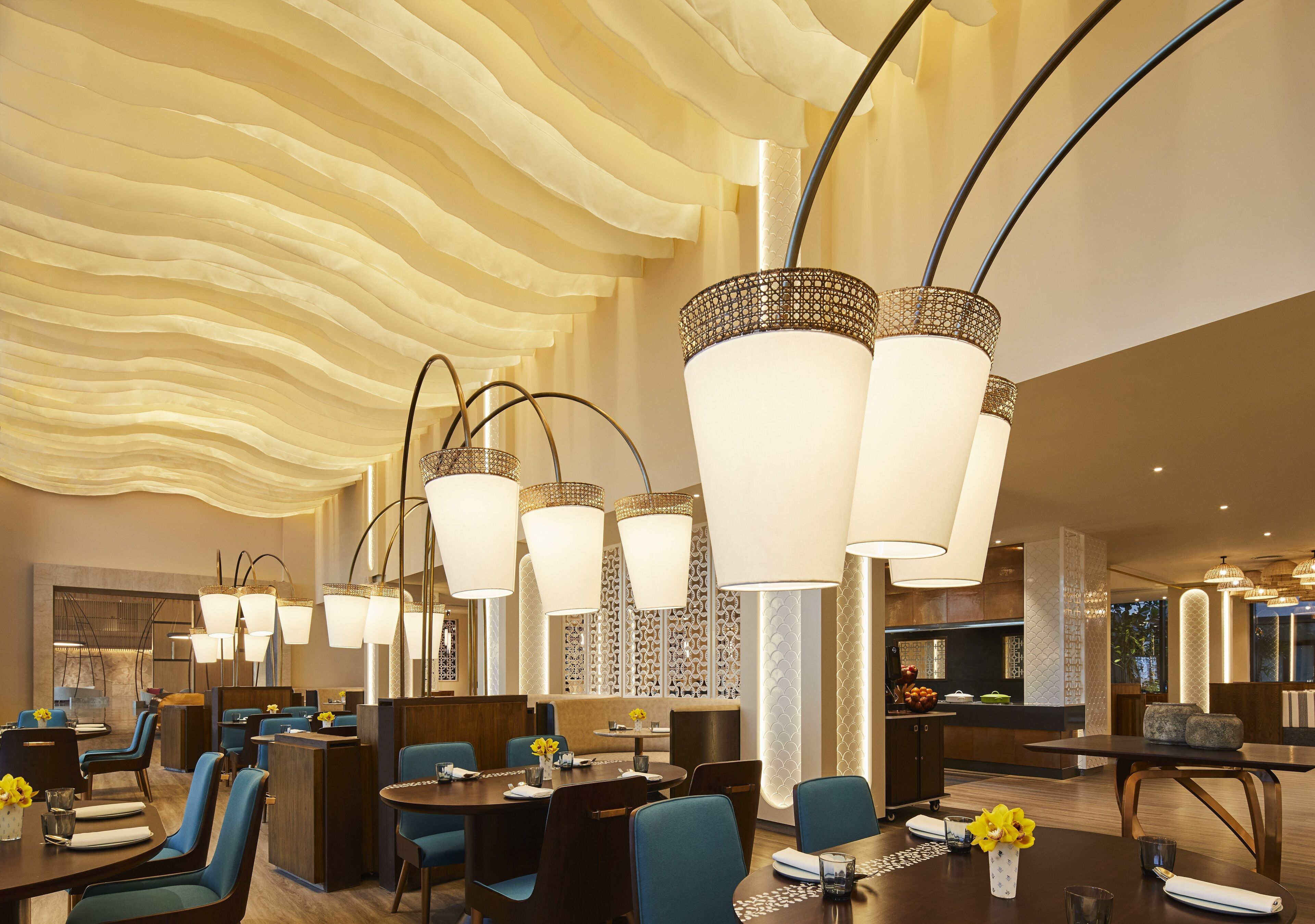 Uma sala de jantar moderna com pé-direito alto, elegantes lustres e uma ilha central.