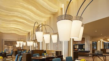 Uma sala de jantar moderna com pé-direito alto, elegantes lustres e uma ilha central.