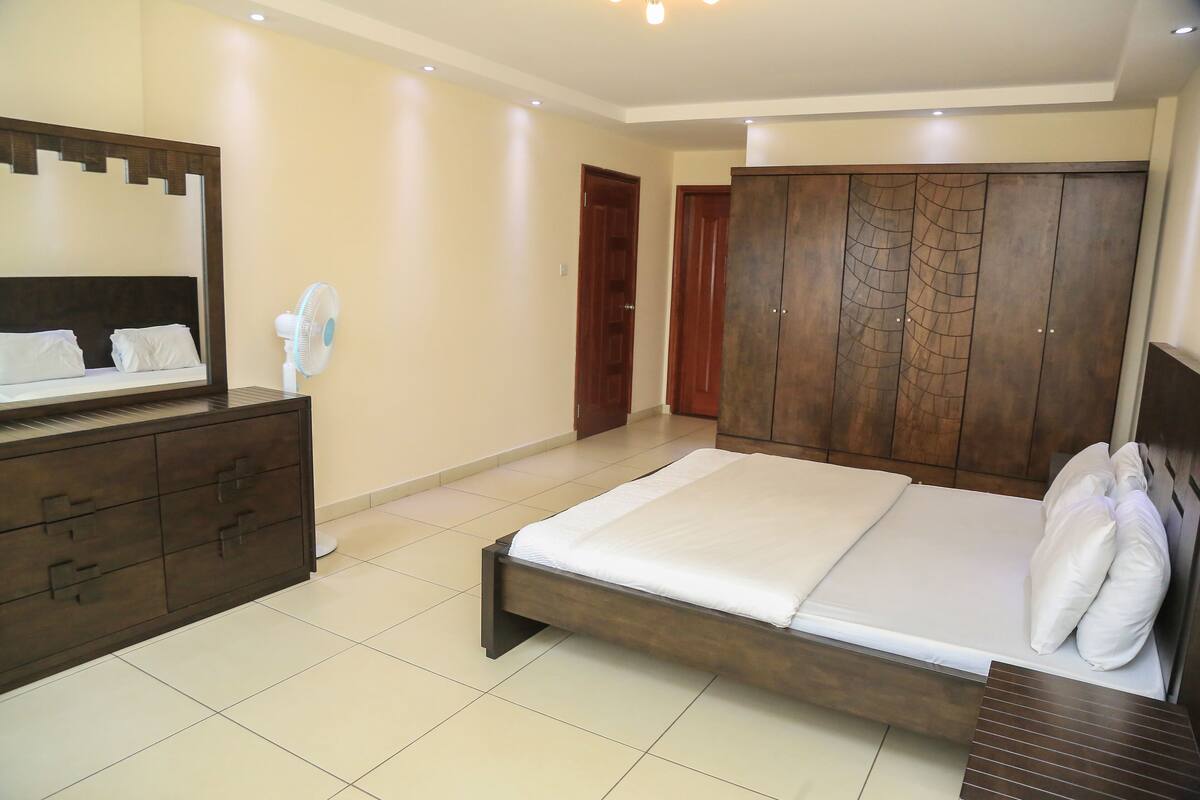 Quarto com cama, penteoude, espelho e guarda-roupa.