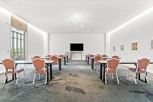 Uma sala de conferências com uma mesa grande, cadeiras, uma TV de tela plana e obras de arte nas paredes.