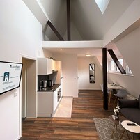 Um apartamento moderno com cozinha, sala de jantar e sala de estar. Uma escadaria liga os dois andares.
