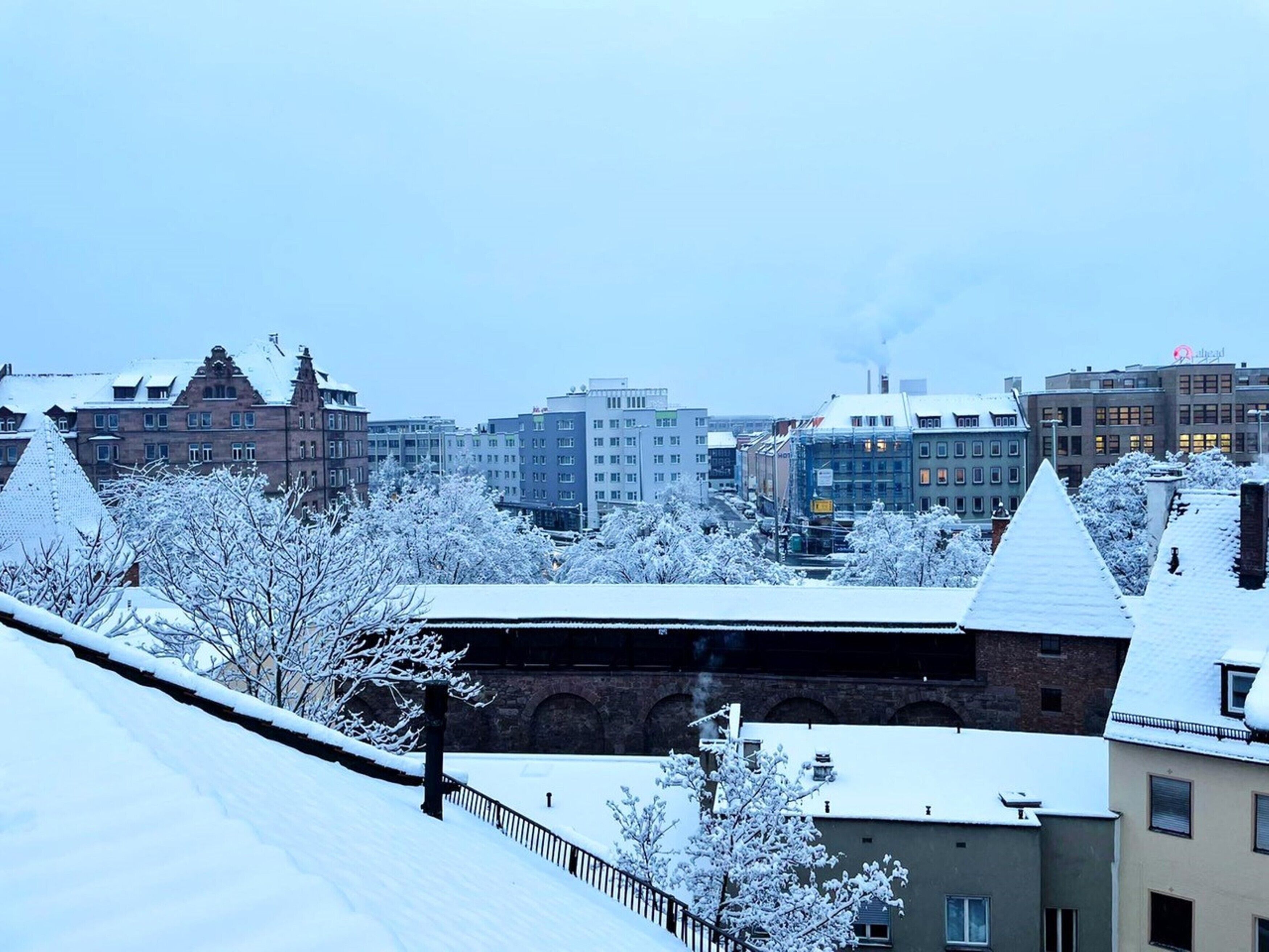 Paisagem urbana com edifícios e árvores cobertos de neve.