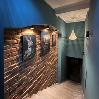 Uma escadaria com parede de tijolos e obras de arte emolduradas.