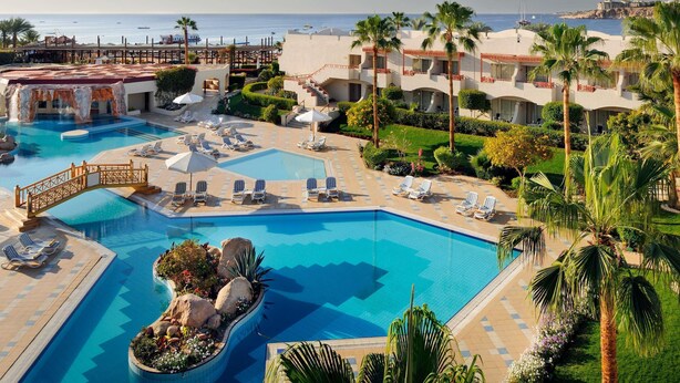 Um resort com uma grande piscina, espreguiçadeiras e vista para o mar.