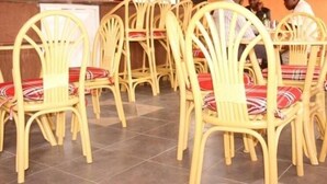 Uma fileira de cadeiras amarelas com almofadas xadrez vermelhas e brancas, dispostas em uma área de refeições.