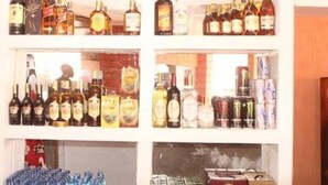 Uma área de bar com prateleiras cheias de garrafas de bebidas diversas.