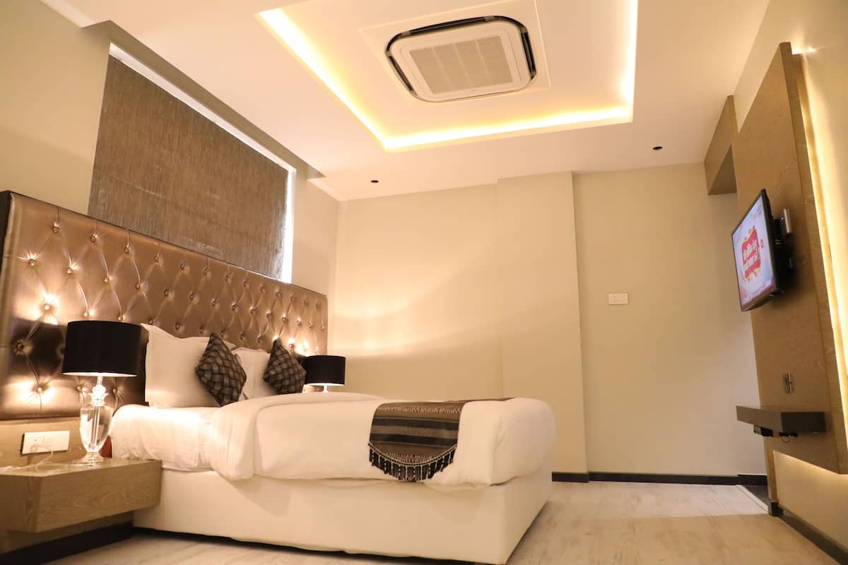 Quarto moderno com cabeceira estofada, luminárias de apoio, televisão de tela plana e uma janela grande.