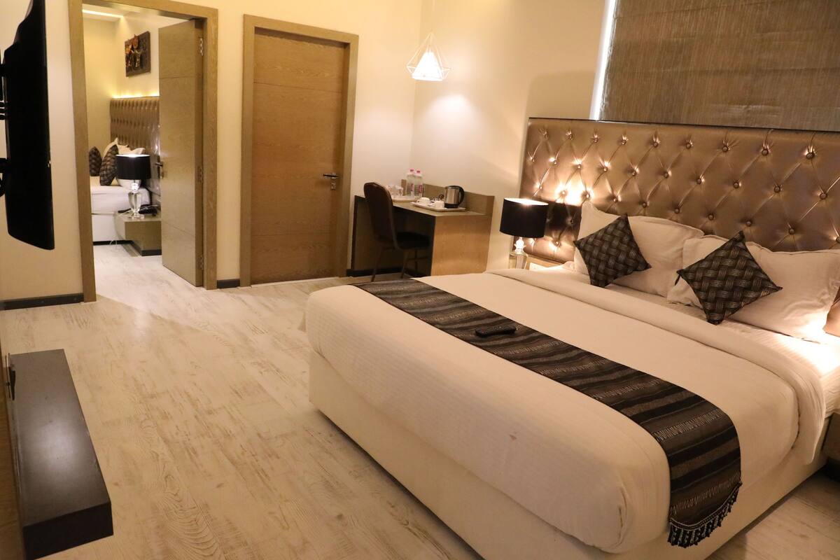 Quarto de hotel com uma cama grande, uma escrivaninha, uma cadeira e um espelho.