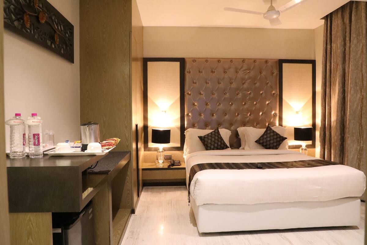 Quarto de hotel com cama, mesas de cabeceira, escrivaninha e ventoinha no teto.