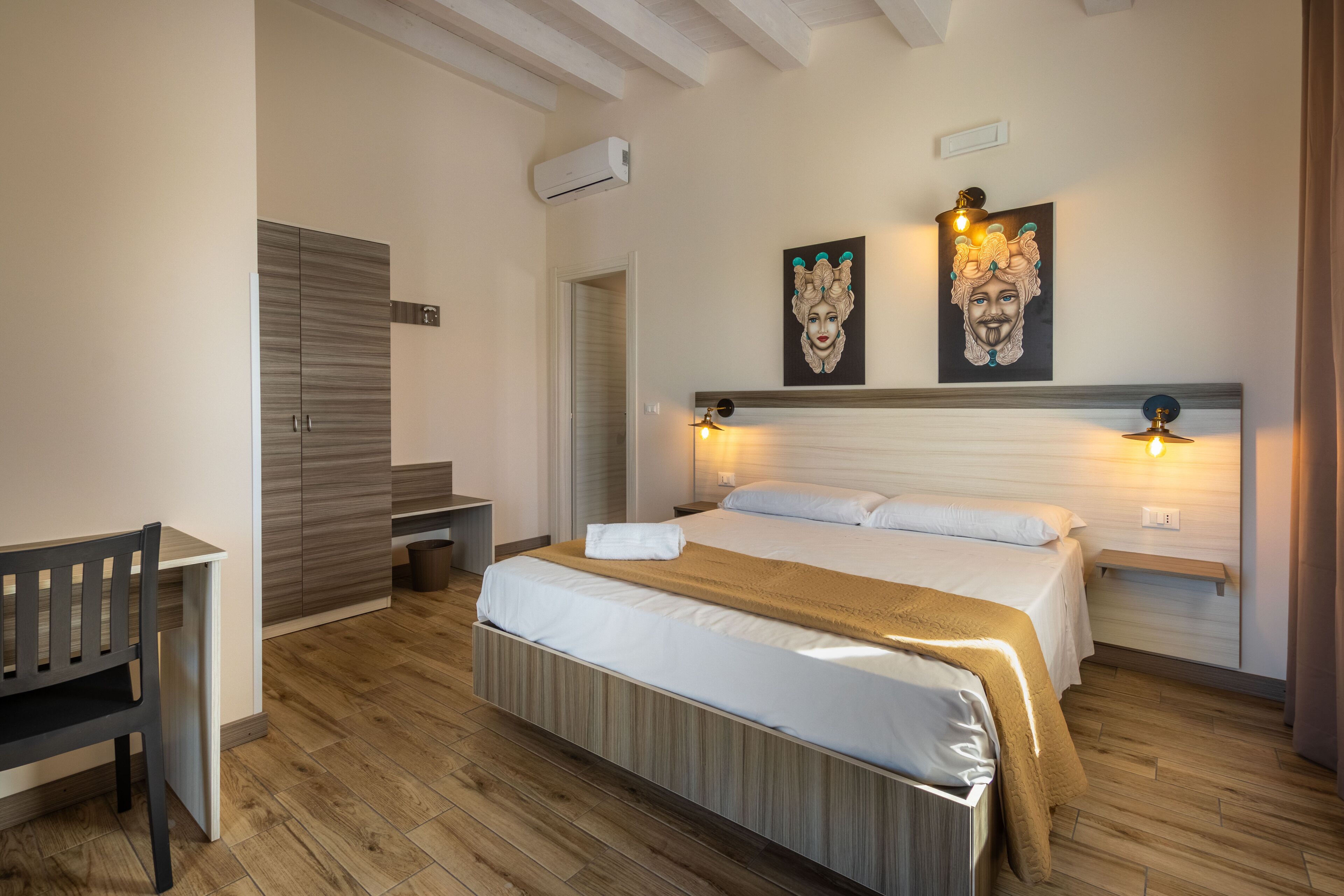 Quarto com cama, mesas de cabeceira, escrivaninha e uma cadeira.