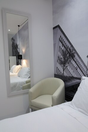 Quarto com cama, cadeira, espelho grande e um mural na parede com a imagem de um edifício.
