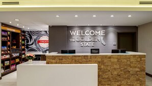 Uma área de recepção com uma placa indicando 'Welcome to the Golden State' e um balcão com a inscrição 'Hilton'.