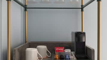 Uma cozinha compacta com cafeteira, duas canecas, uma placa vermelha e diversos objetos pequenos em uma bancada.