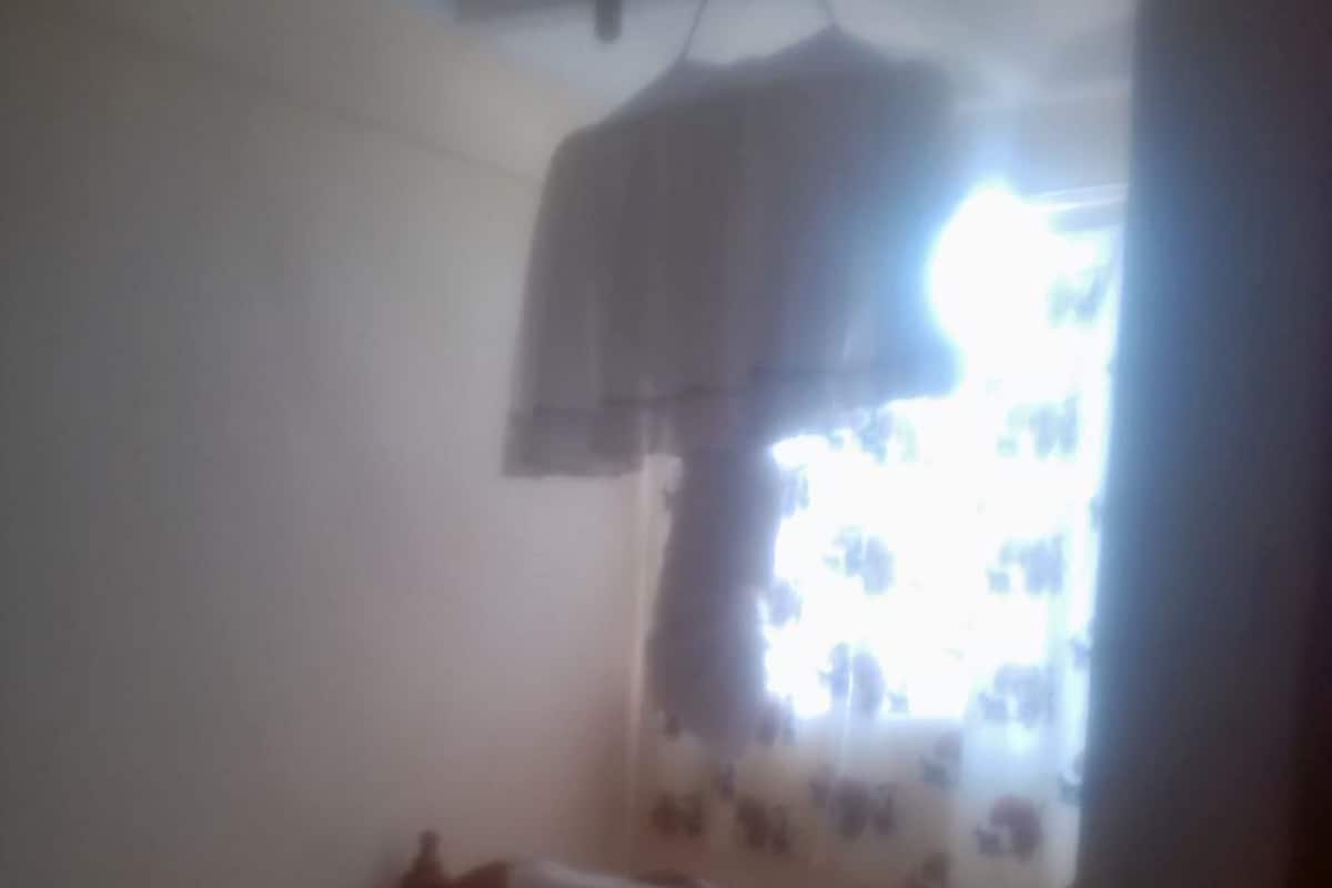 Quarto com cama, janela com cortinas e luminária suspensa.