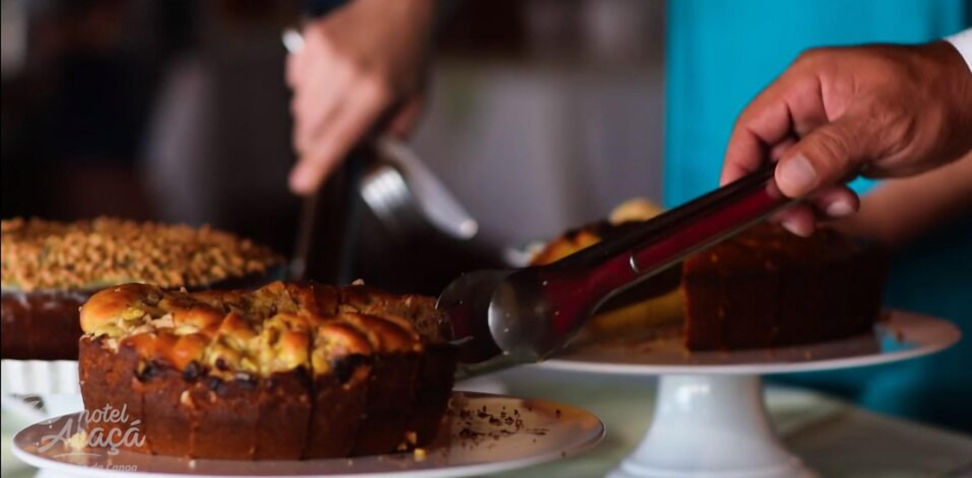 Uma pessoa corta uma barra de pão com uma faca e pinças.