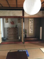 Um quarto japonês tradicional com tatames, um armário de madeira, um lanterna de papel pendurada e um biombos shoji com caligrafia.
