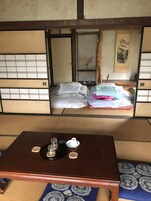 Um quarto japonês tradicional com tatames, uma mesa de madeira baixa com utensílios de chá e futons.