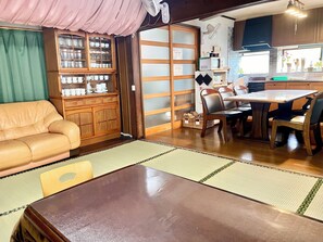 Uma sala de estar japonesa tradicional com tatames, uma mesa de madeira baixa e um sofá.