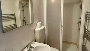 Uma casa de banho com lavatório, sanita e cabine de duche com parede de vidro.