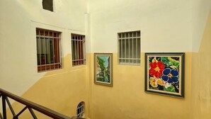 Uma escadaria com corrimão de metal, um claraboia e duas janelas com grades.