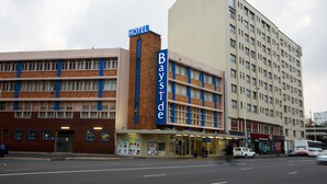 Um hotel com um letreiro de 'Bayside' em destaque, fachada de tijolos e um edifício moderno adjacente.