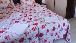 Uma cama bem arrumada com roupa de cama floral, um quadro na parede e um guarda-roupa.