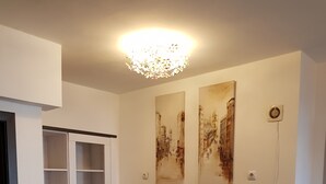 Um quarto com um armário branco, uma luminária no teto e duas pinturas penduradas na parede.