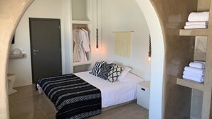 Quarto com cama, mesas de cabeceira, guarda-roupa e luminária suspensa.