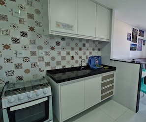 Cozinha com azulejos estampados, fogão a gás, pia e geladeira.