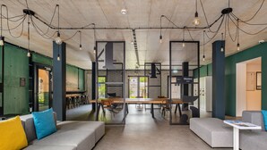Um espaço de escritório moderno com uma grande mesa de reuniões, sofás cinzentos e uma placa com a inscrição numastays.com.