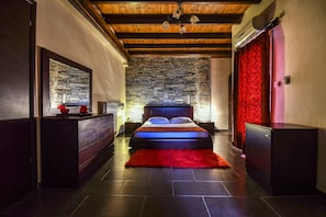 Quarto moderno com parede de pedra, teto de madeira e tapete vermelho.