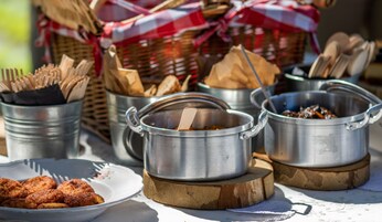 Exposição de comida com panelas e cestos de metal, um prato de comida frita e tábuas de servir de madeira.