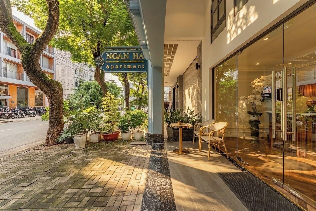 Um edifício com uma placa indicando 'Ngan Ha Apartment' e entrada pela porta de vidro.