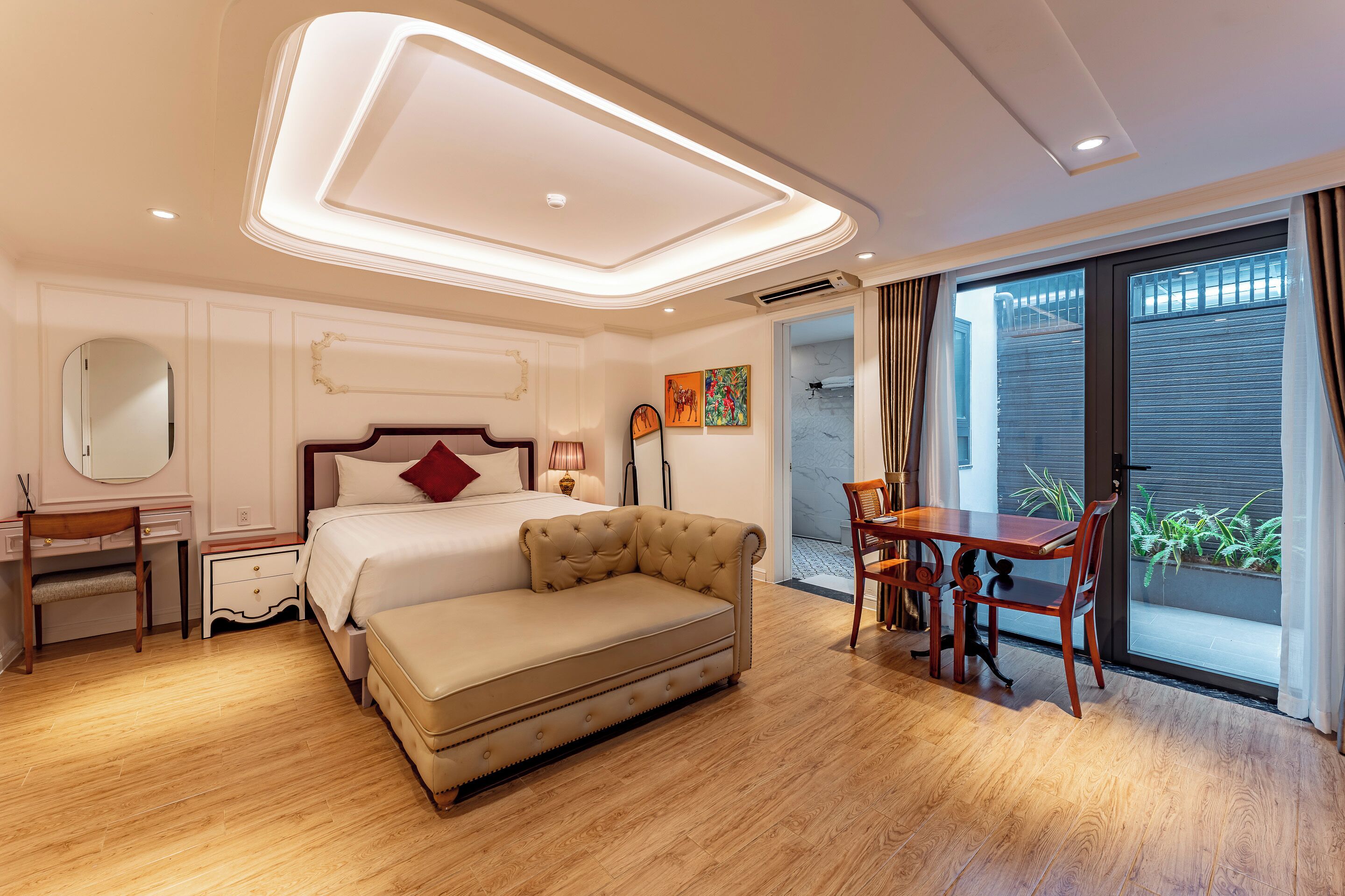 Quarto de hotel com cama, sofá, escrivaninha e área de refeições.