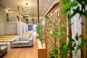 Um hall de hotel com um sofá, piso de madeira e uma planta.