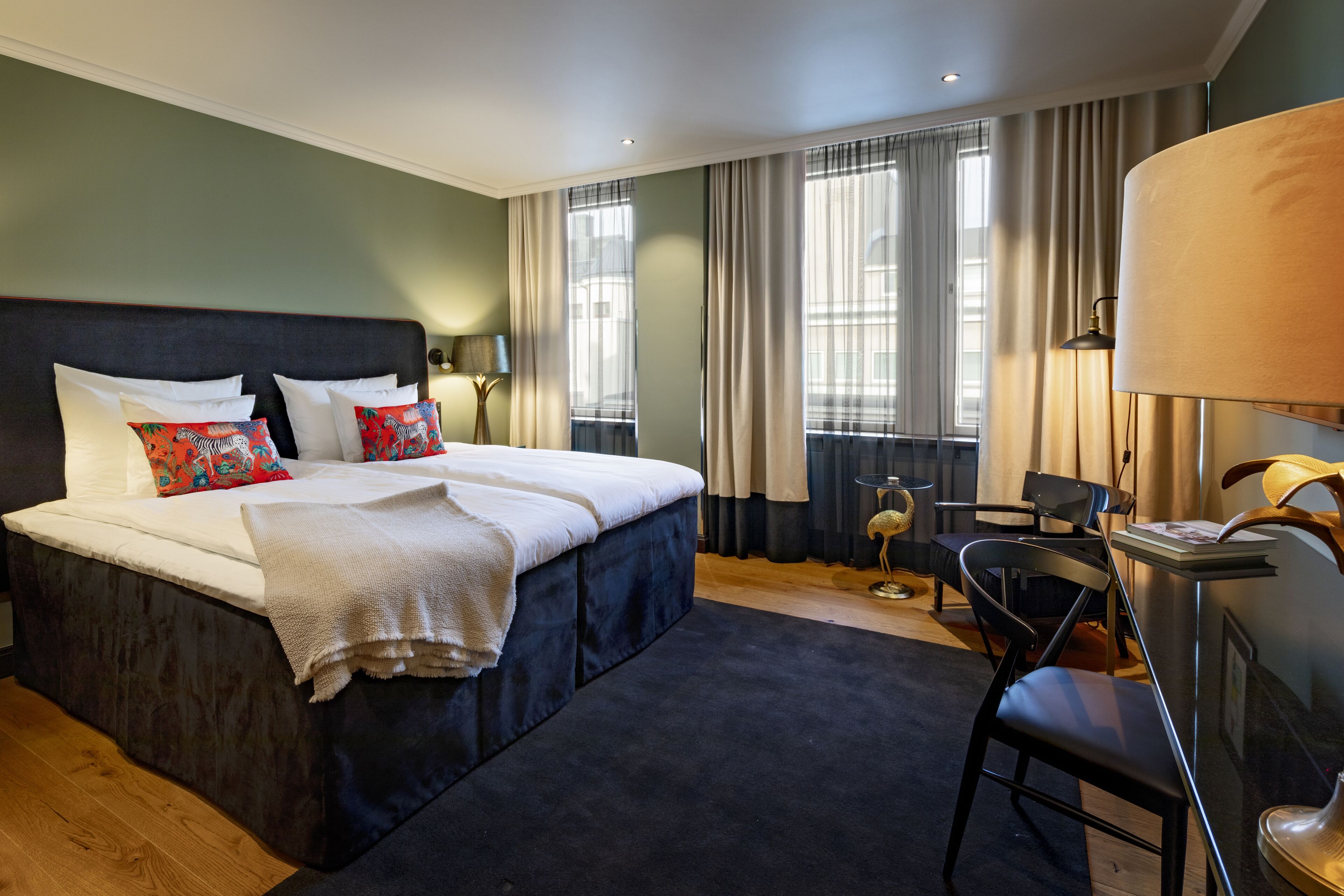 Quarto de hotel com uma cama grande, uma escrivaninha e uma cadeira.