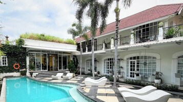 Um edifício de dois andares com piscina, área de estar externa e varanda.
